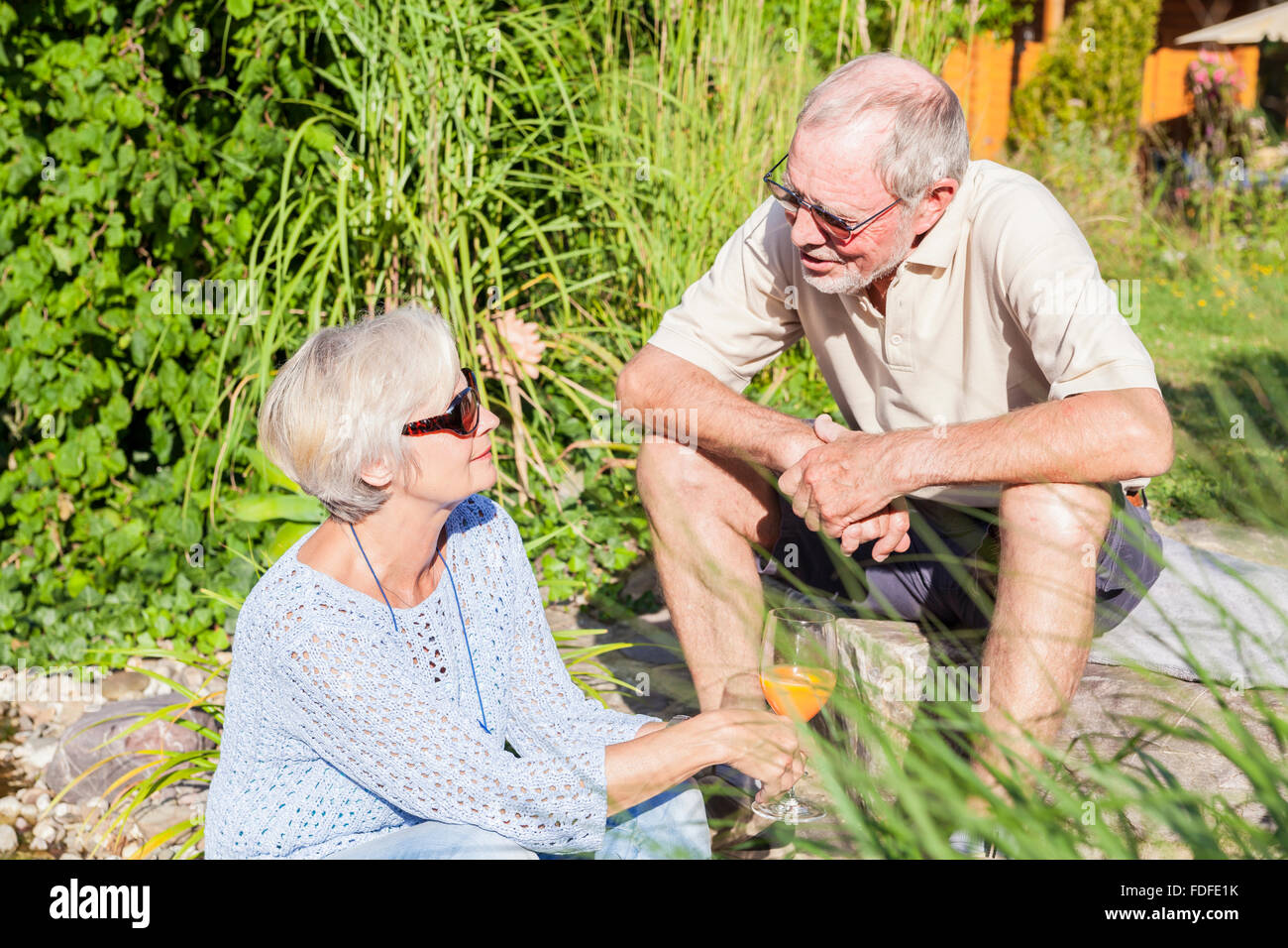 happy senior couple in garden smiling and laughing in sunshine enjoying ...