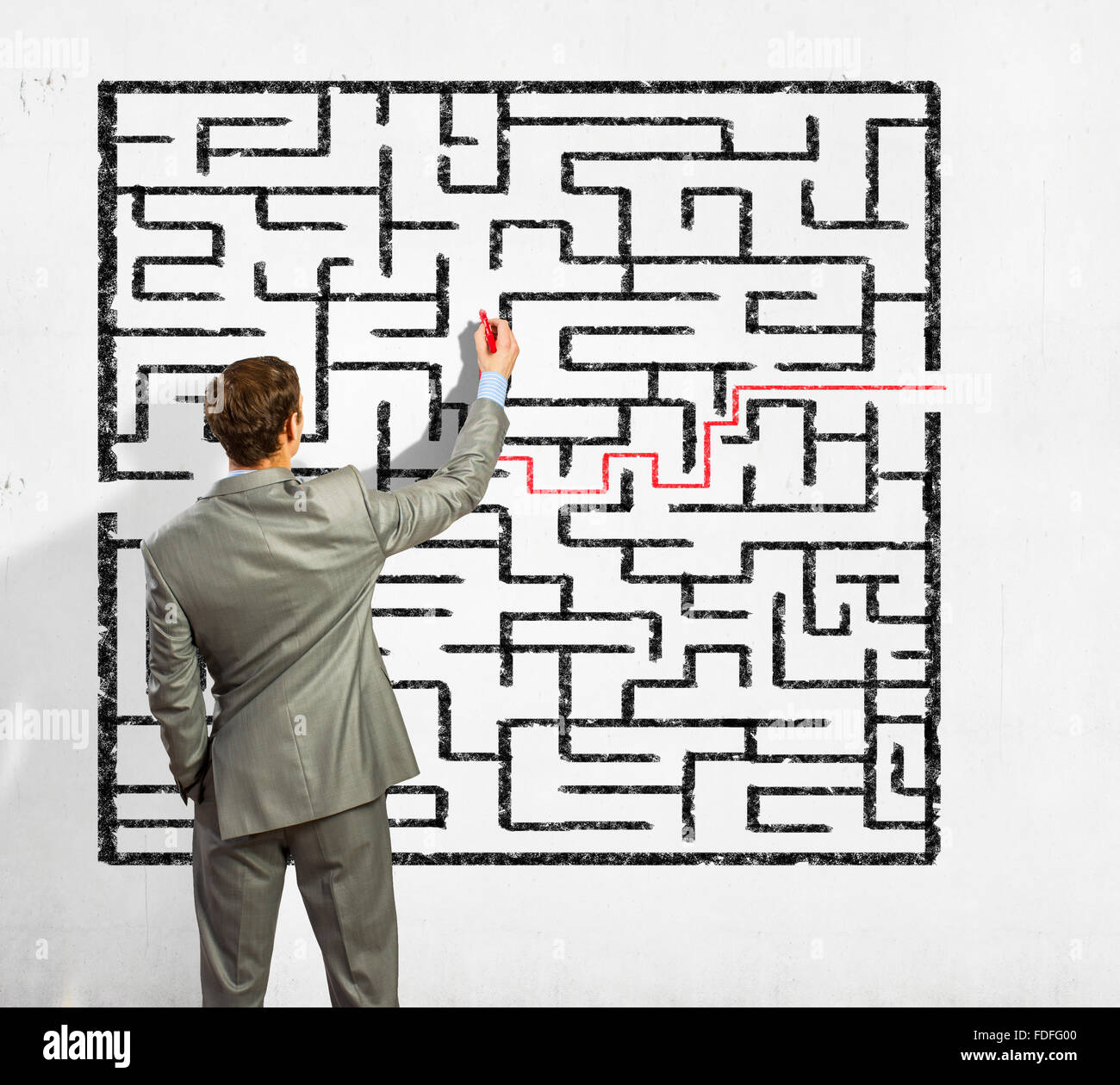 Back view image of young businessman trying to find way out of maze ...