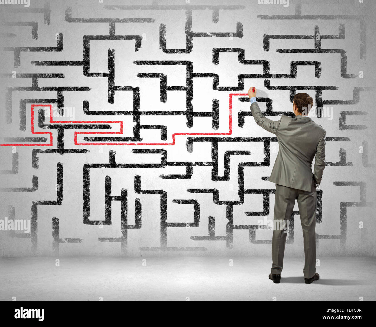 Back view image of young businessman trying to find way out of maze ...