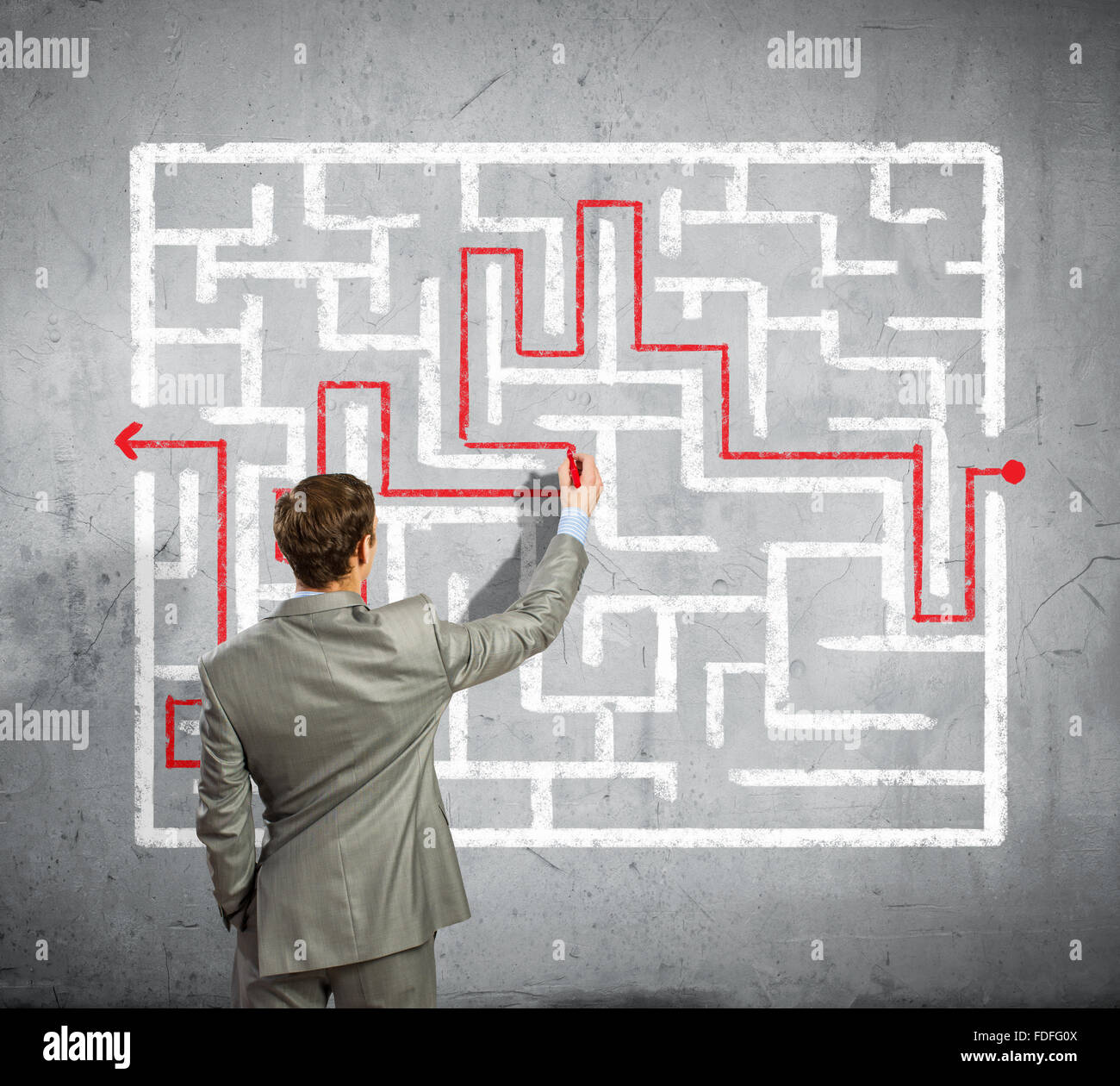 Back view image of young businessman trying to find way out of maze ...