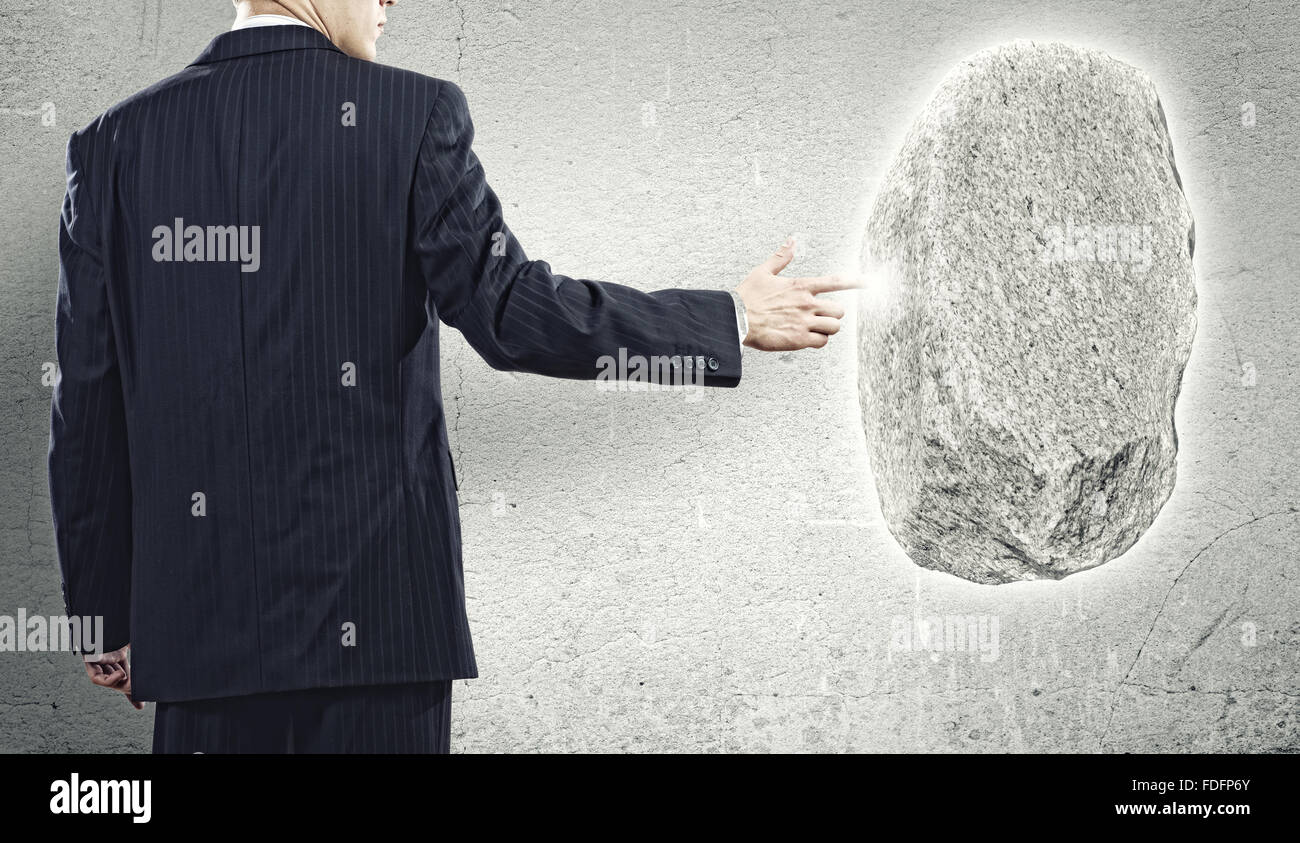 Businessman in suit huge holding stone in palm Stock Photo - Alamy
