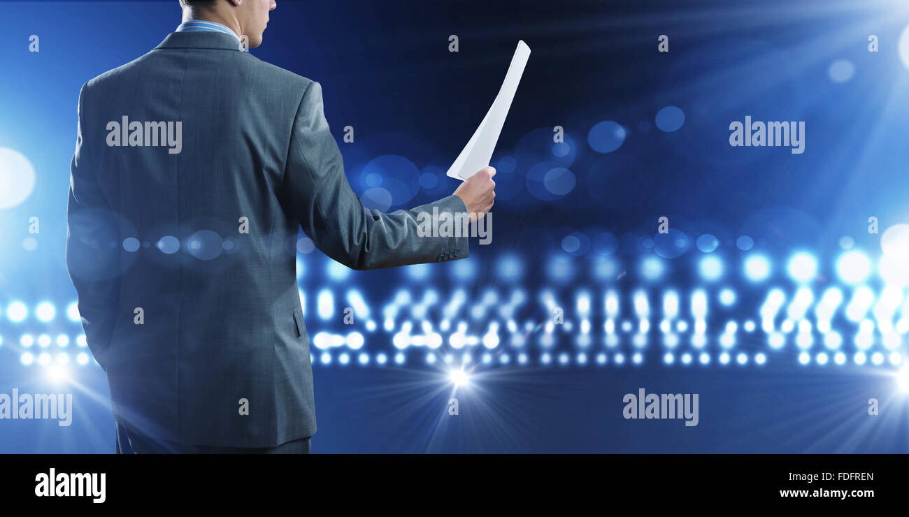 Back view of businessman speaker standing on podium in lights Stock ...