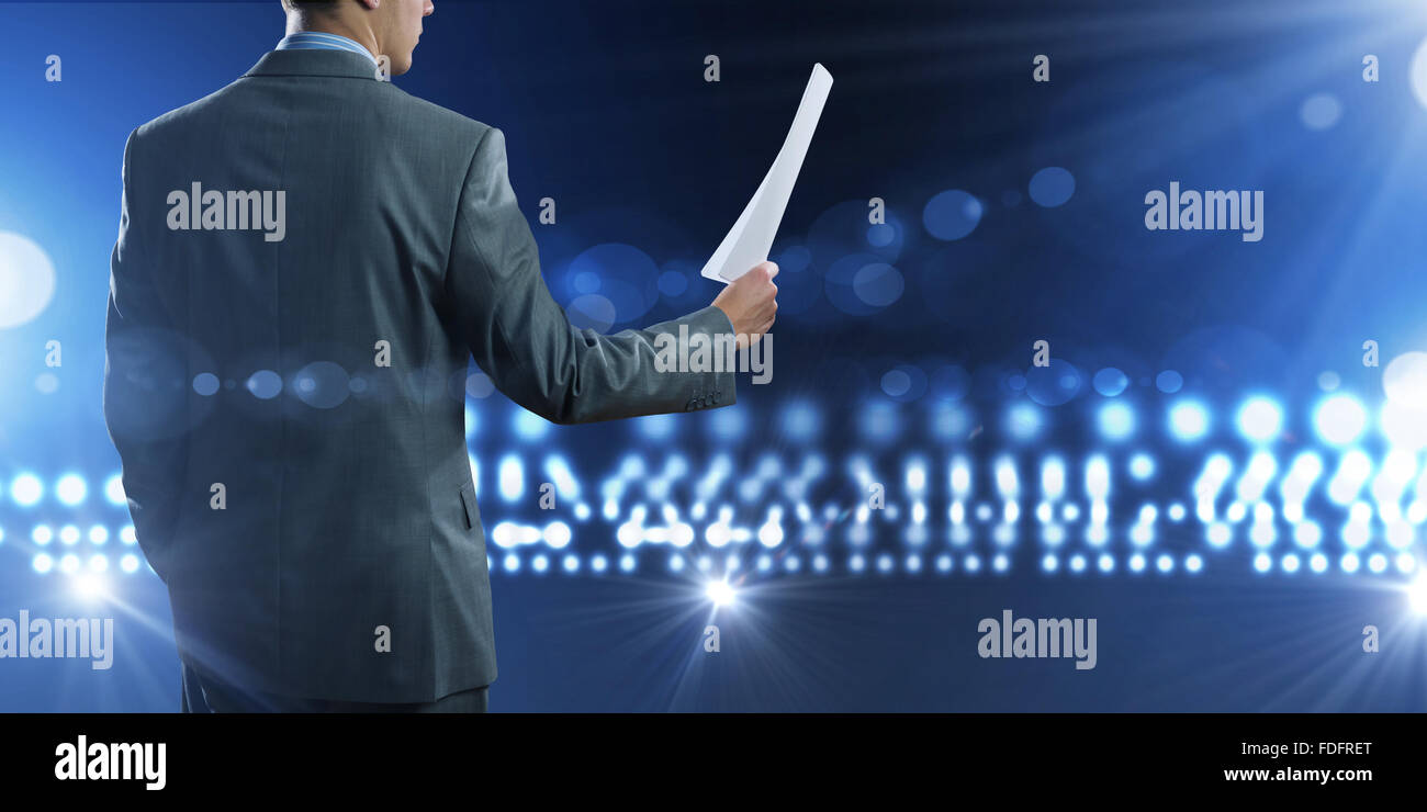 Back view of businessman speaker standing on podium in lights Stock ...