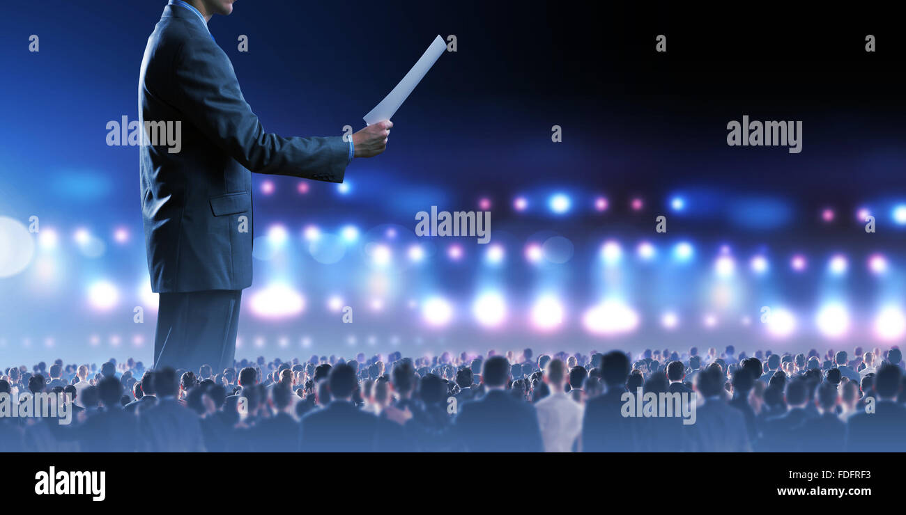 Back view of businessman speaker standing on podium in lights Stock ...