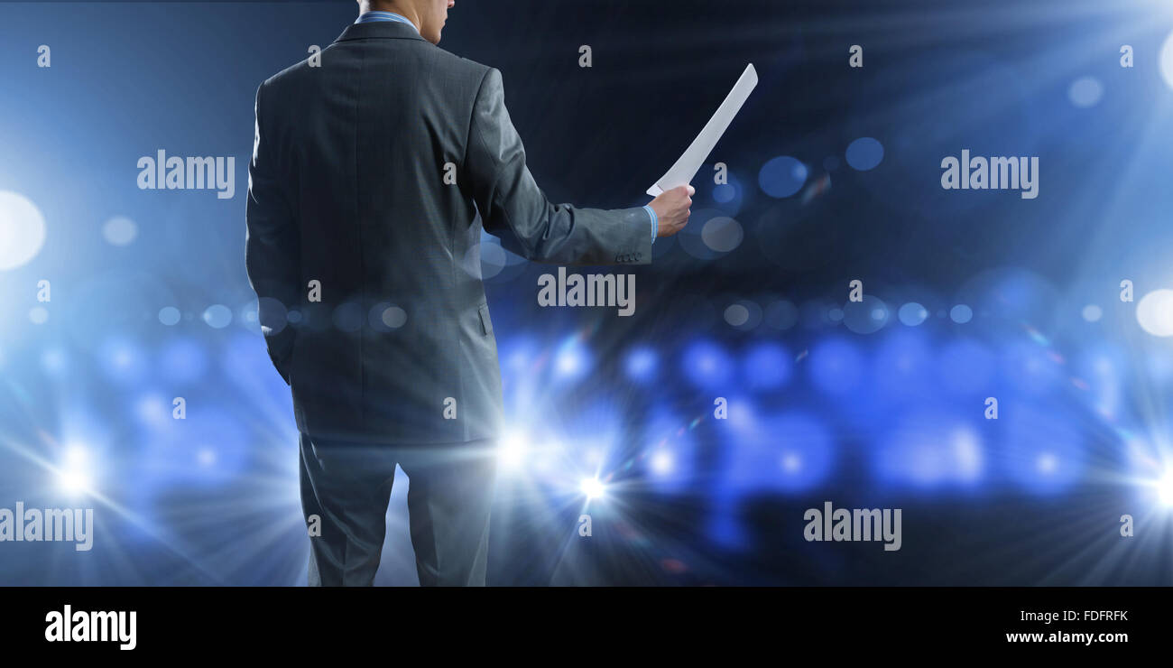 Back view of businessman speaker standing on podium in lights Stock ...