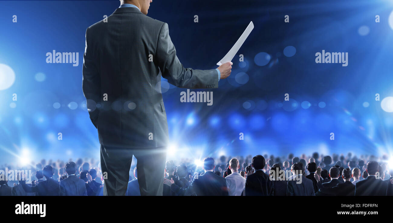Back view of businessman speaker standing on podium in lights Stock ...