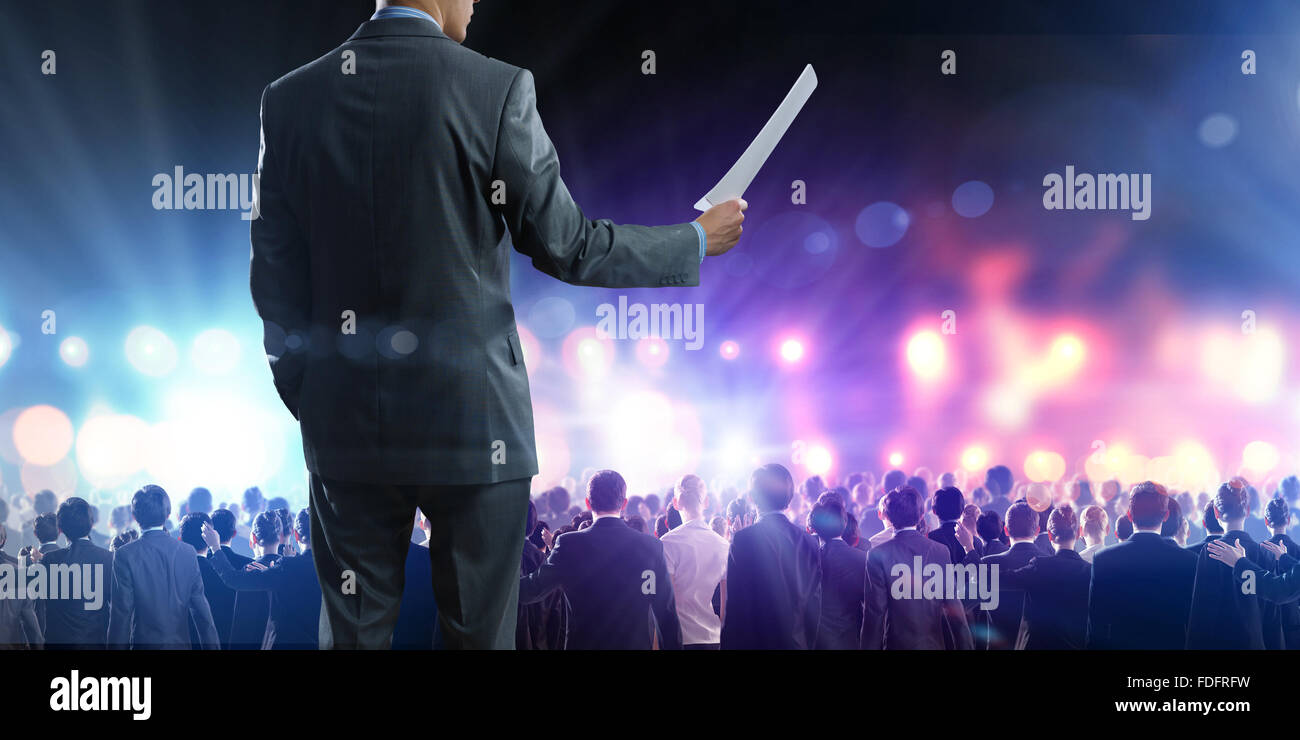 Back view of businessman speaker standing on podium in lights Stock ...