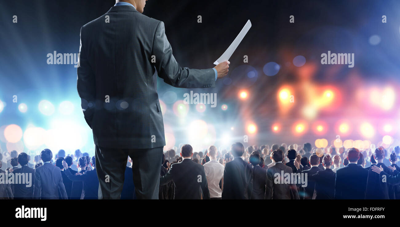 Back view of businessman speaker standing on podium in lights Stock ...