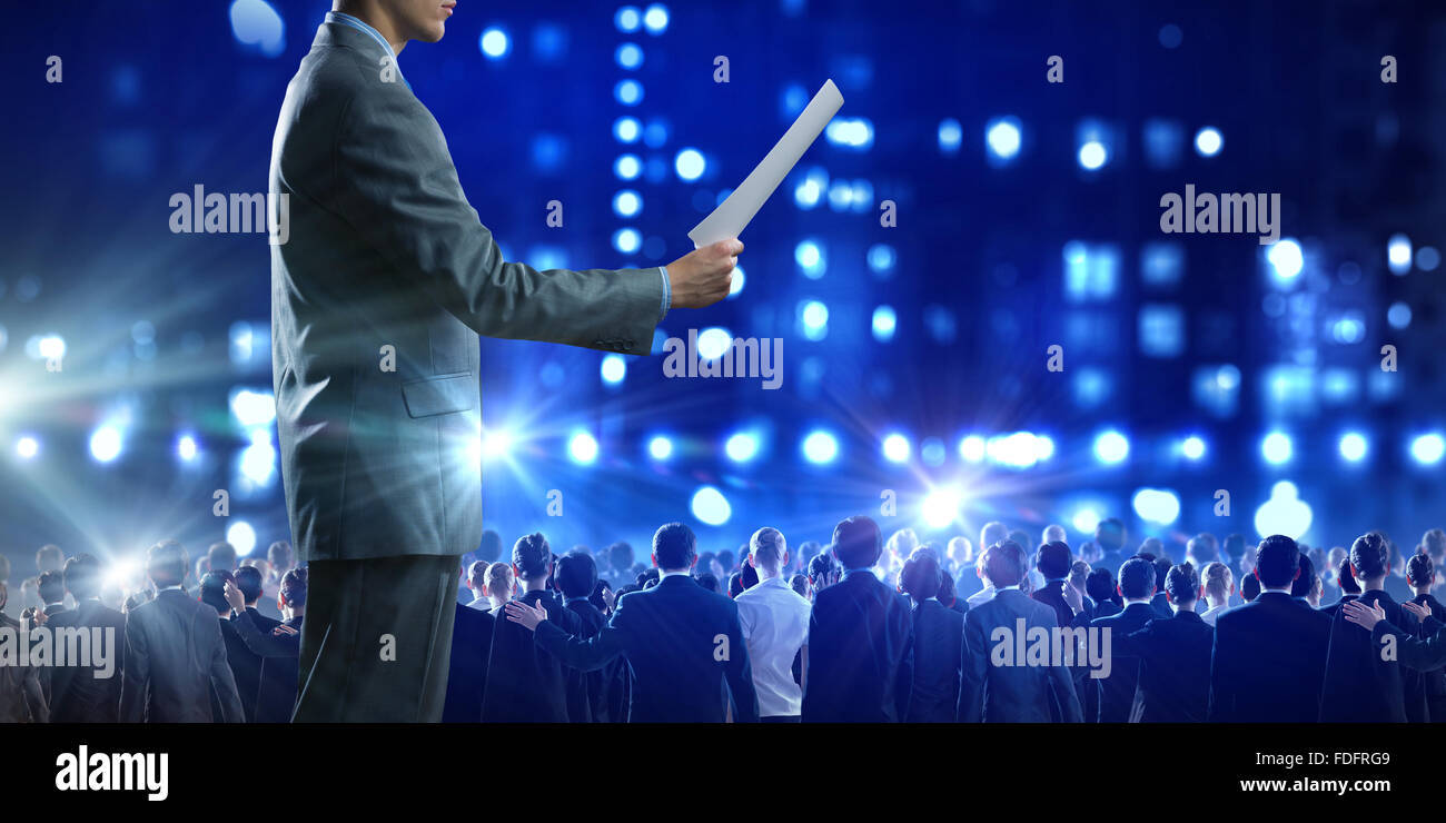 Back view of businessman speaker standing on podium in lights Stock ...