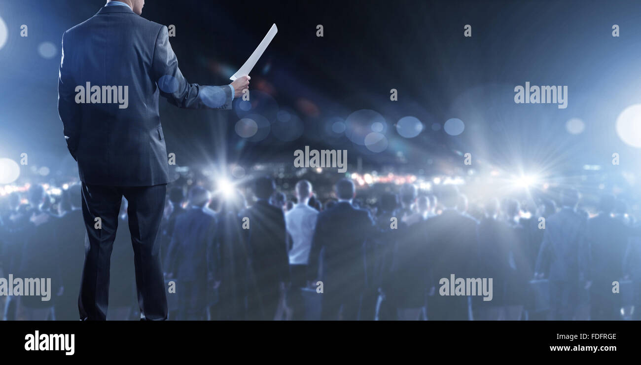Back view of businessman speaker standing on podium in lights Stock ...