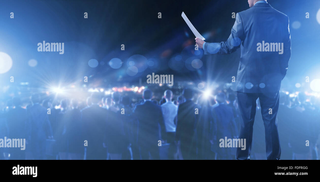 Back view of businessman speaker standing on podium in lights Stock ...