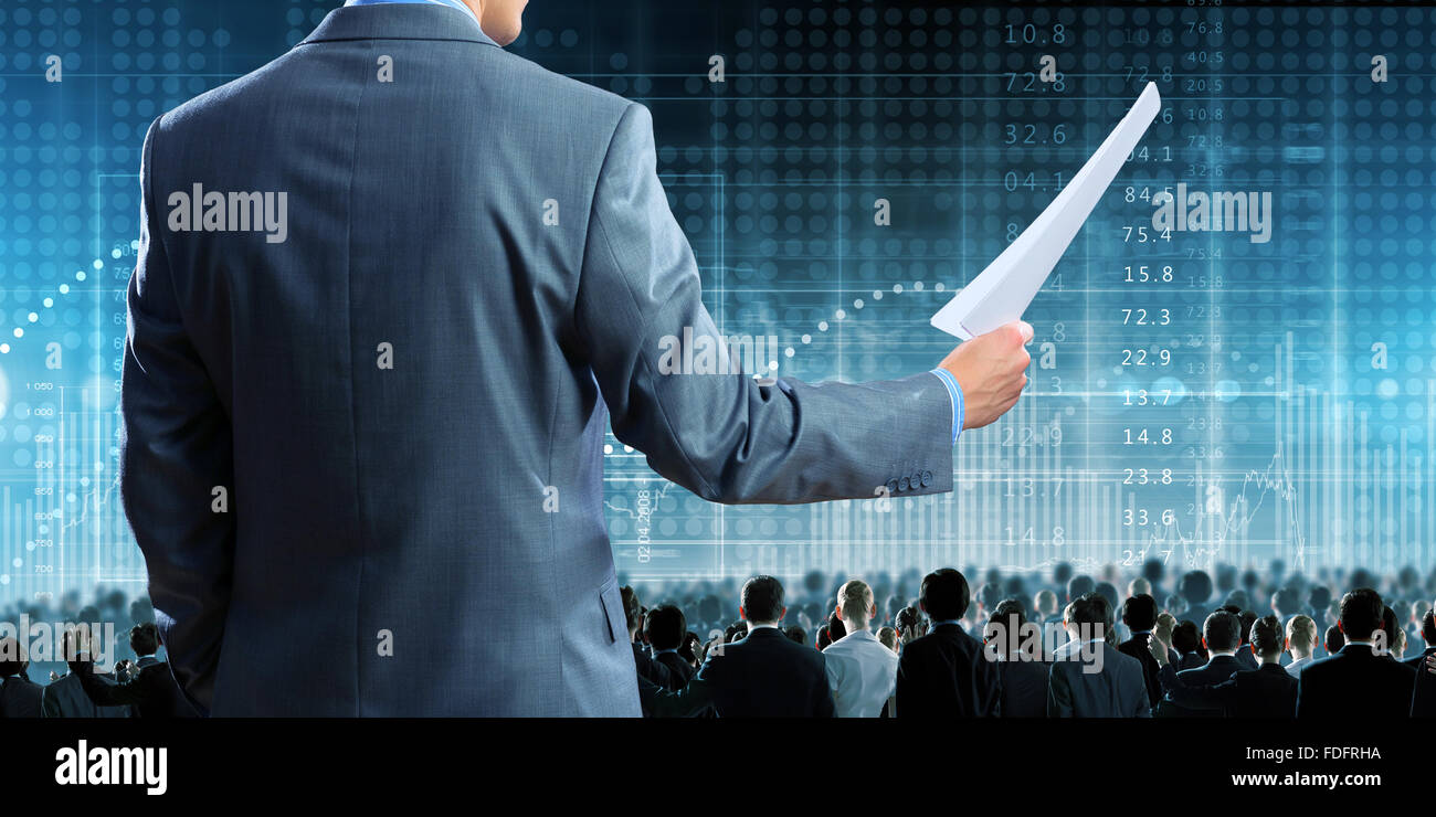 Back view of businessman speaker standing on podium in lights Stock ...