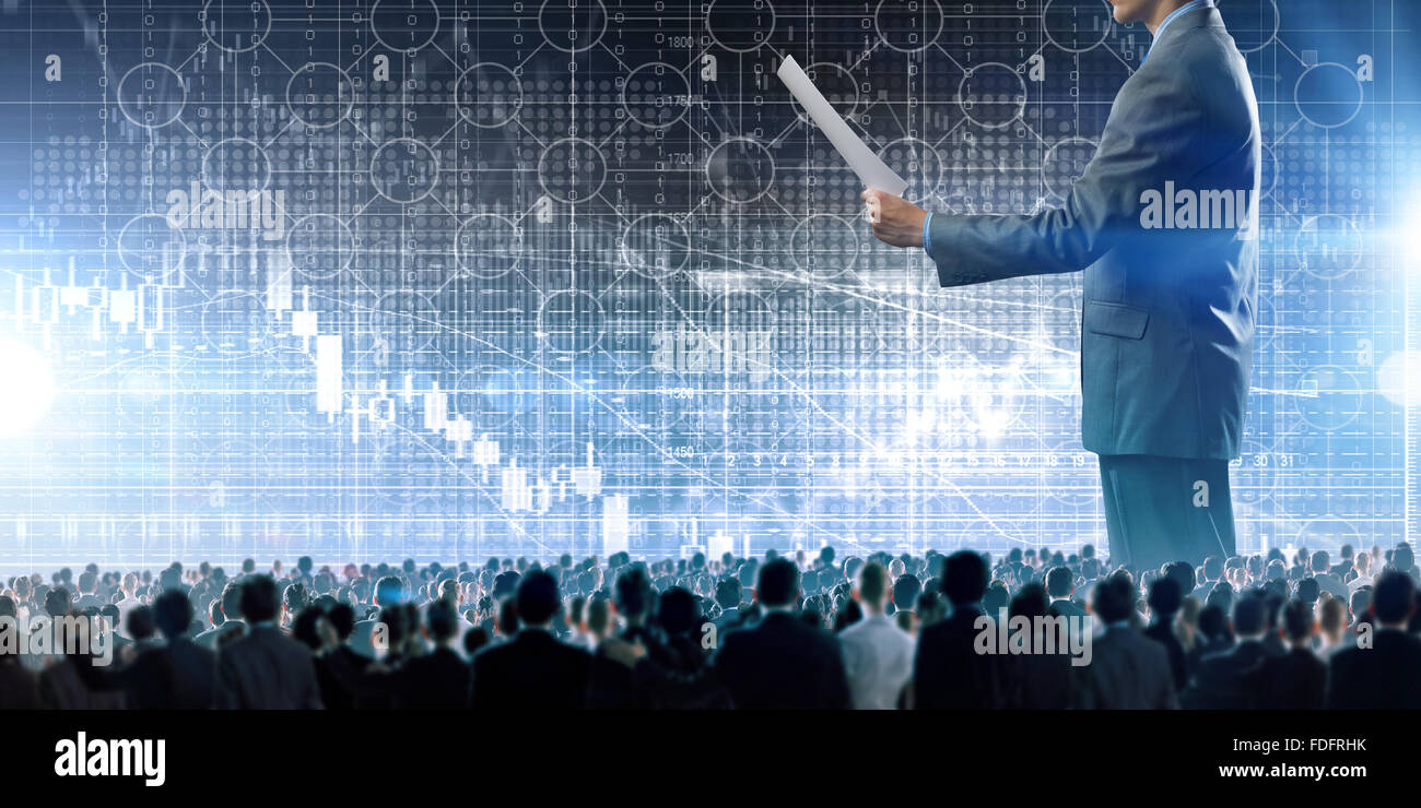 Back view of businessman speaker standing on podium with papers in hand ...