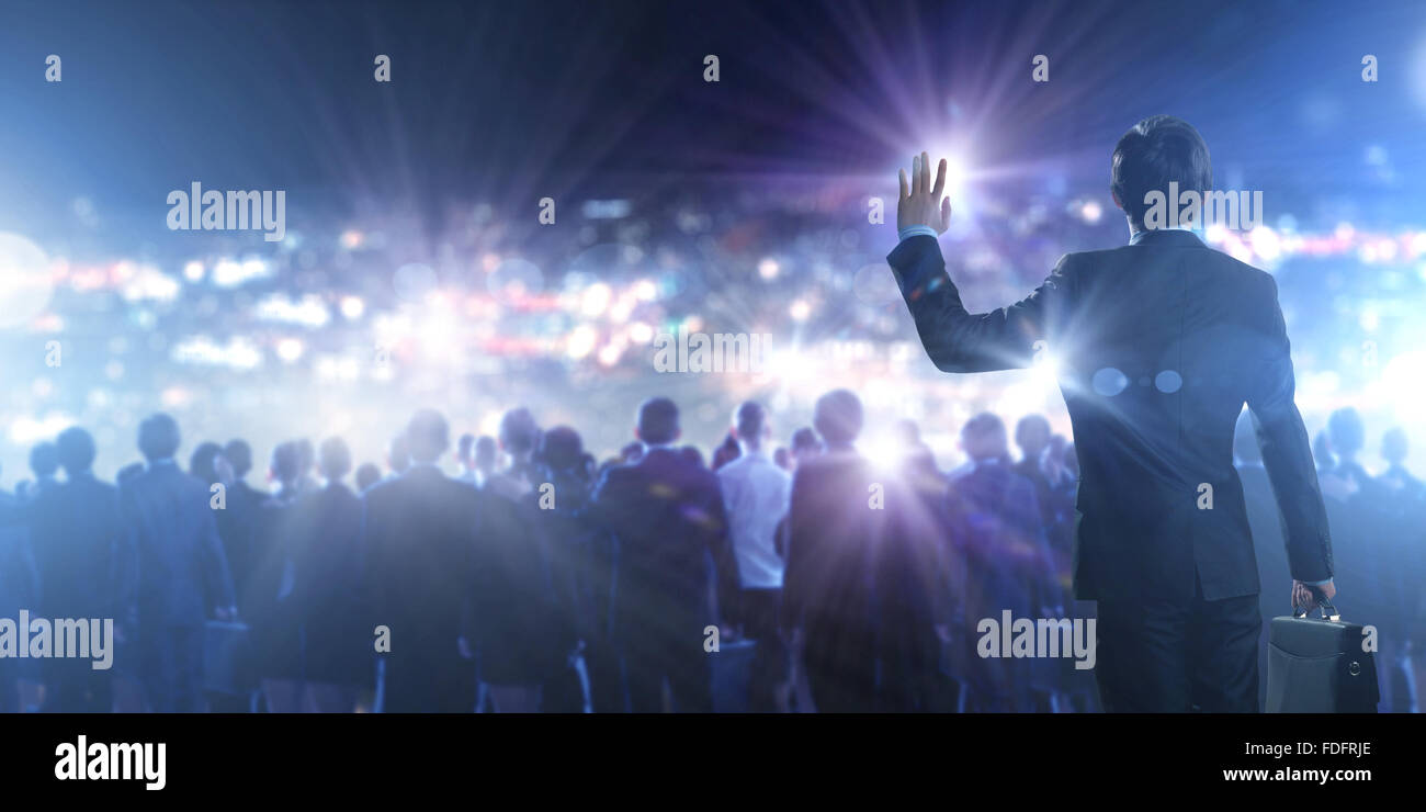 Back view of businessman speaker standing on podium in lights Stock ...