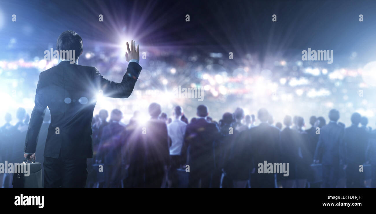 Back view of businessman speaker standing on podium in lights Stock ...