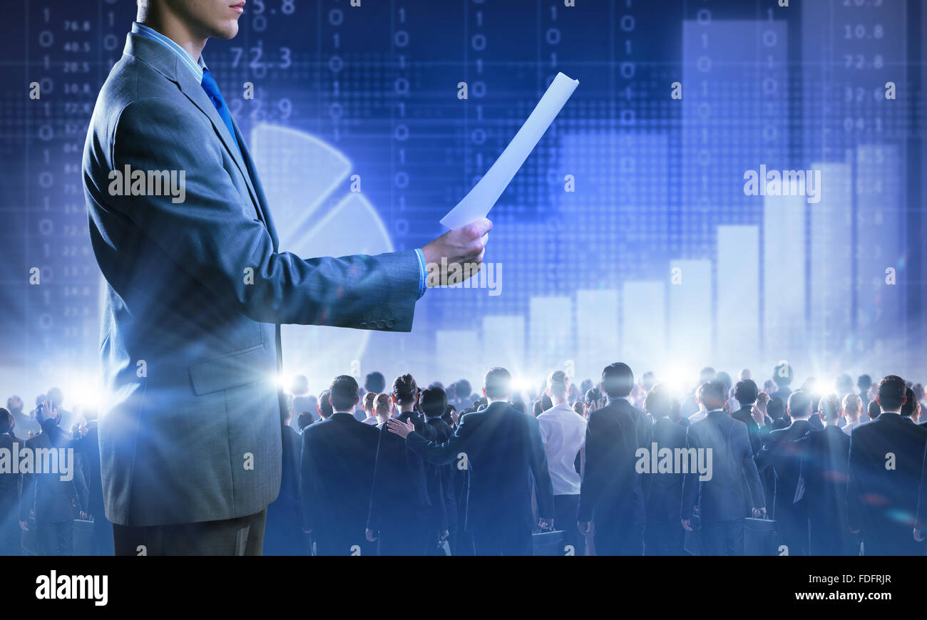 Back view of businessman speaker standing on podium with papers in hand ...