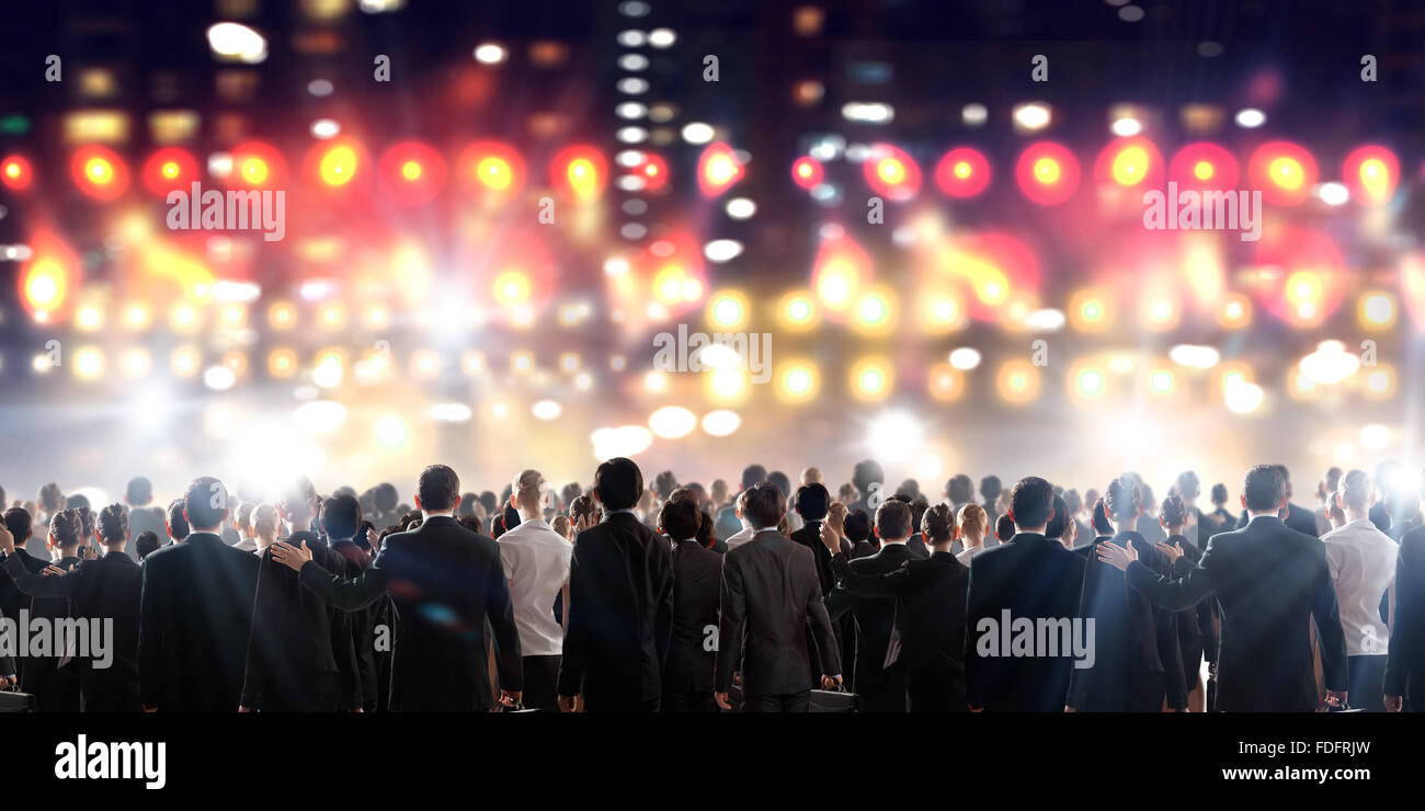 Crowd of businesspeople standing with back with lights at background ...