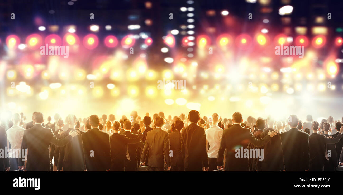 Crowd of businesspeople standing with back with lights at background ...