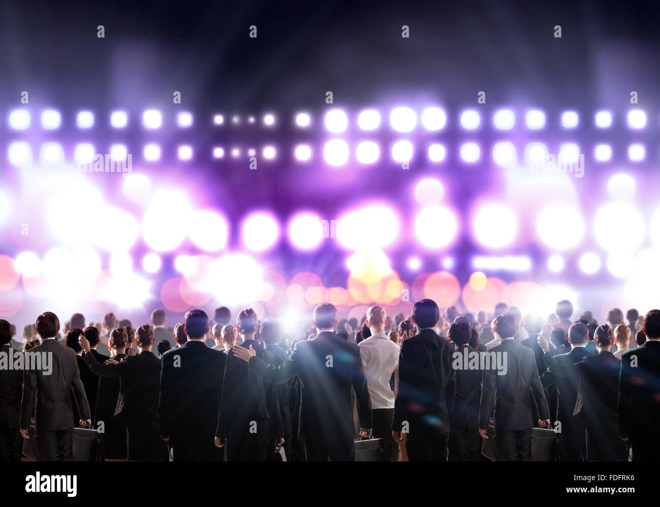 Crowd of businesspeople standing with back with lights at background ...