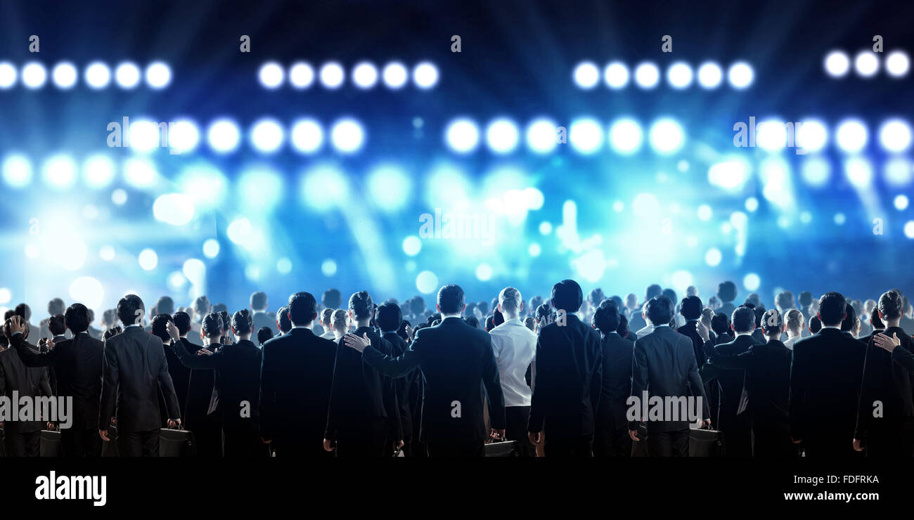 Crowd of businesspeople standing with back with lights at background ...