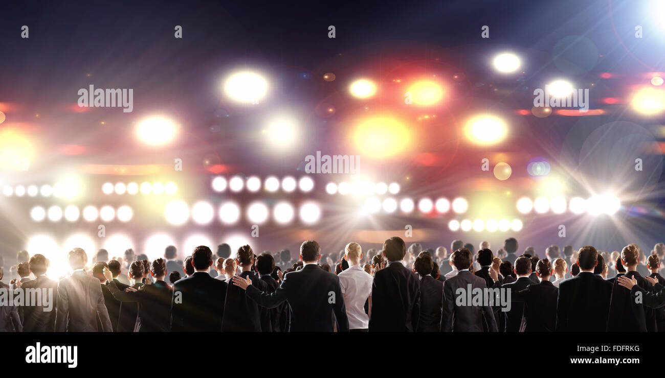 Crowd of businesspeople standing with back with lights at background ...