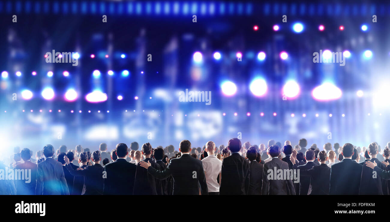Crowd of businesspeople standing with back with lights at background ...