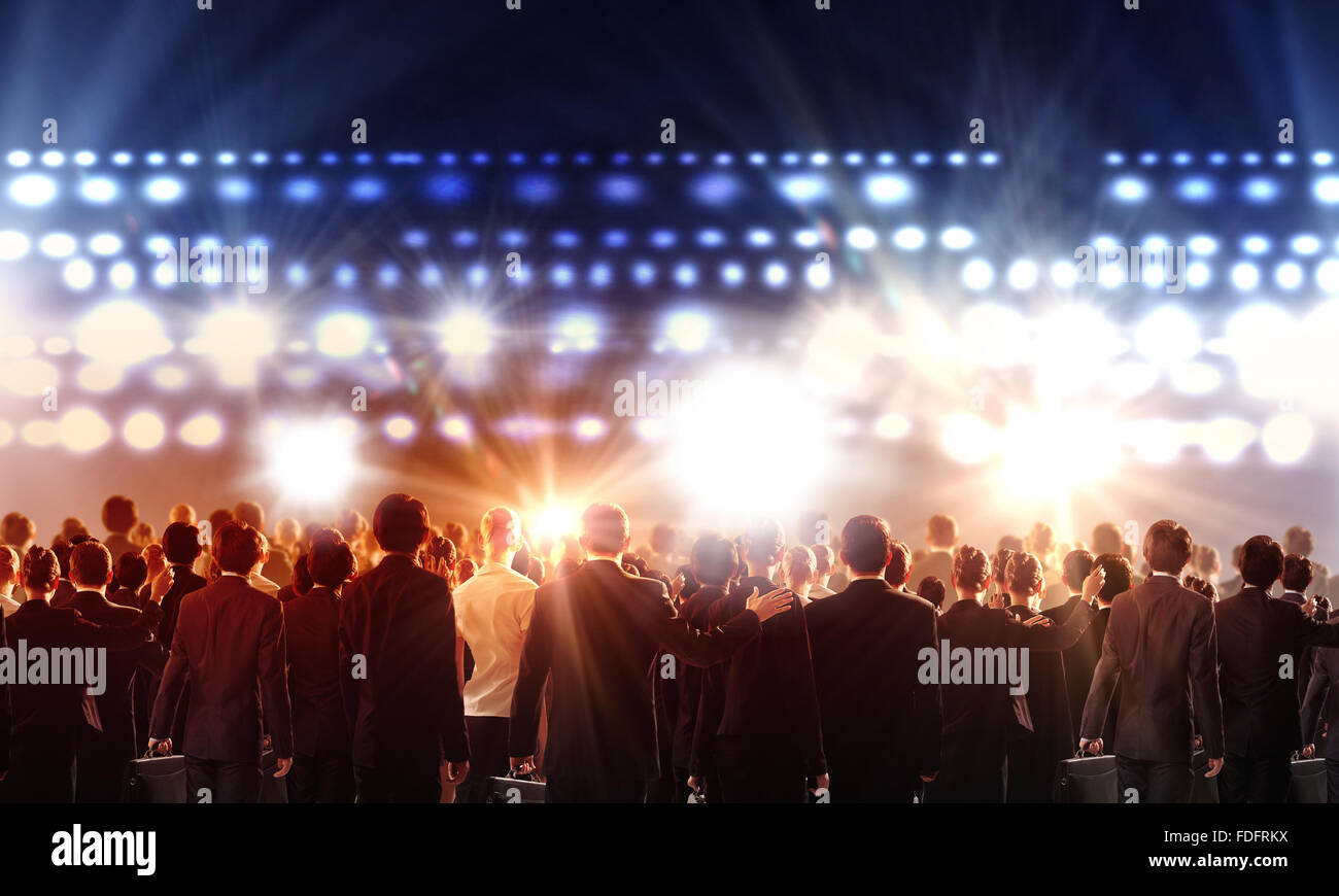 Crowd of businesspeople standing with back with lights at background ...