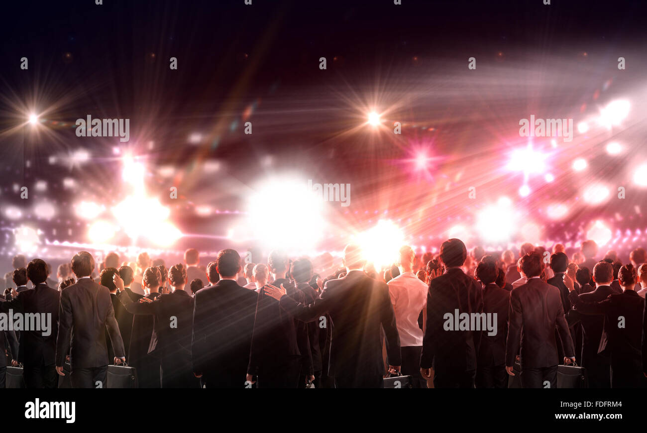 Crowd of businesspeople standing with back with lights at background ...