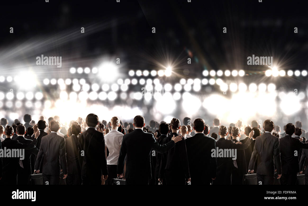 Crowd of businesspeople standing with back with lights at background ...