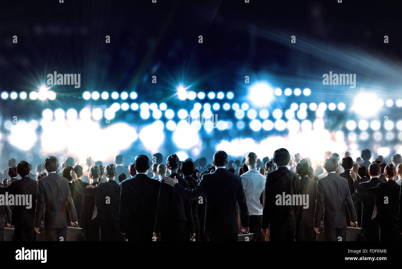 Crowd of businesspeople standing with back with lights at background ...