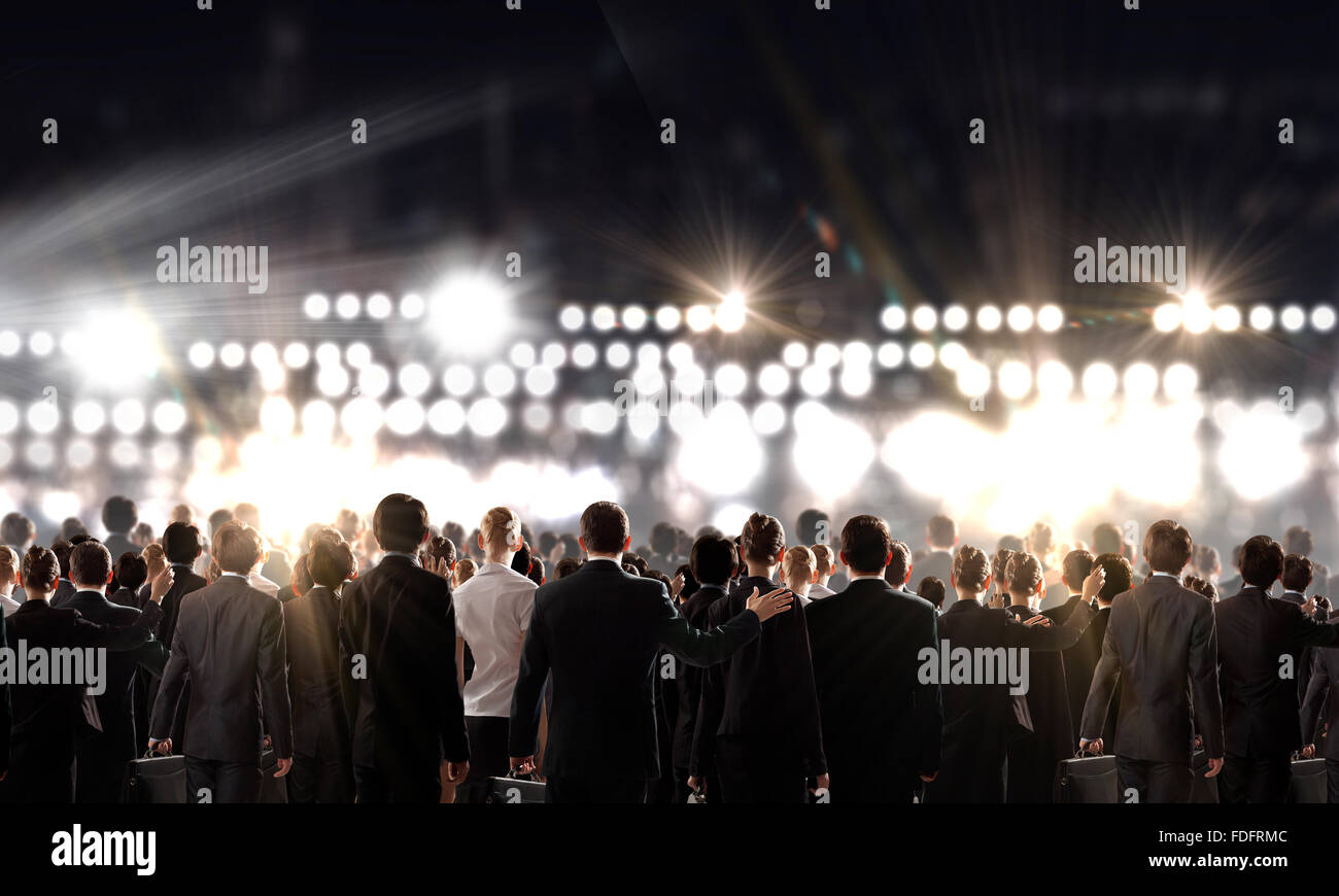 Crowd of businesspeople standing with back with lights at background ...