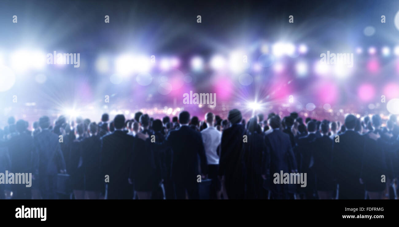 Crowd of businesspeople standing with back with lights at background ...