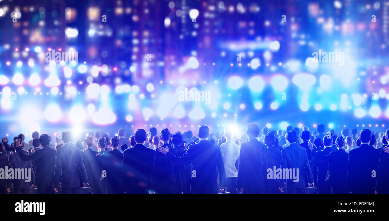 Crowd of businesspeople standing with back with lights at background ...