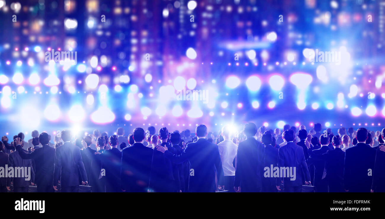 Crowd of businesspeople standing with back with lights at background ...
