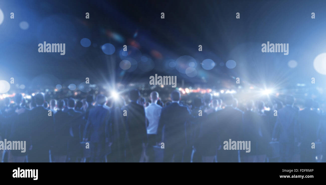 Crowd of businesspeople standing with back with lights at background ...
