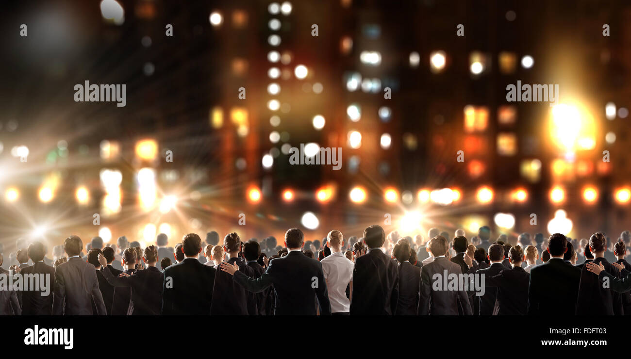 Crowd of businesspeople standing with back with lights at background ...