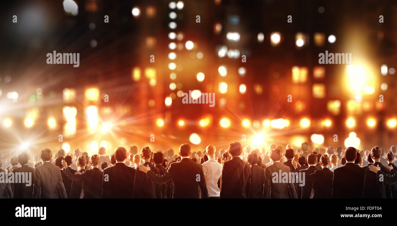 Crowd of businesspeople standing with back with lights at background ...