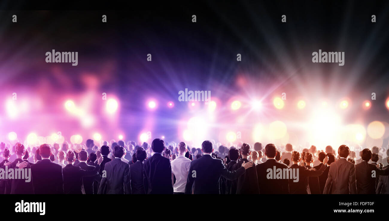 Crowd of businesspeople standing with back with lights at background ...