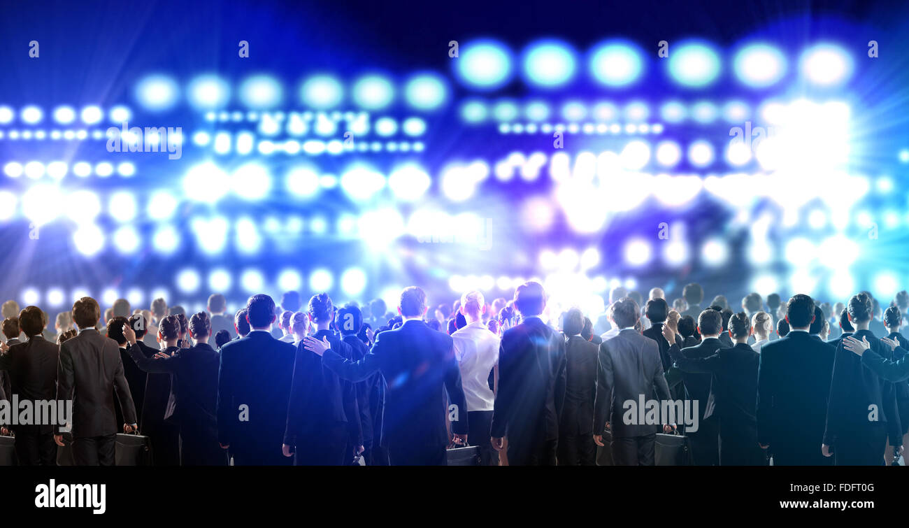 Crowd of businesspeople standing with back with lights at background ...