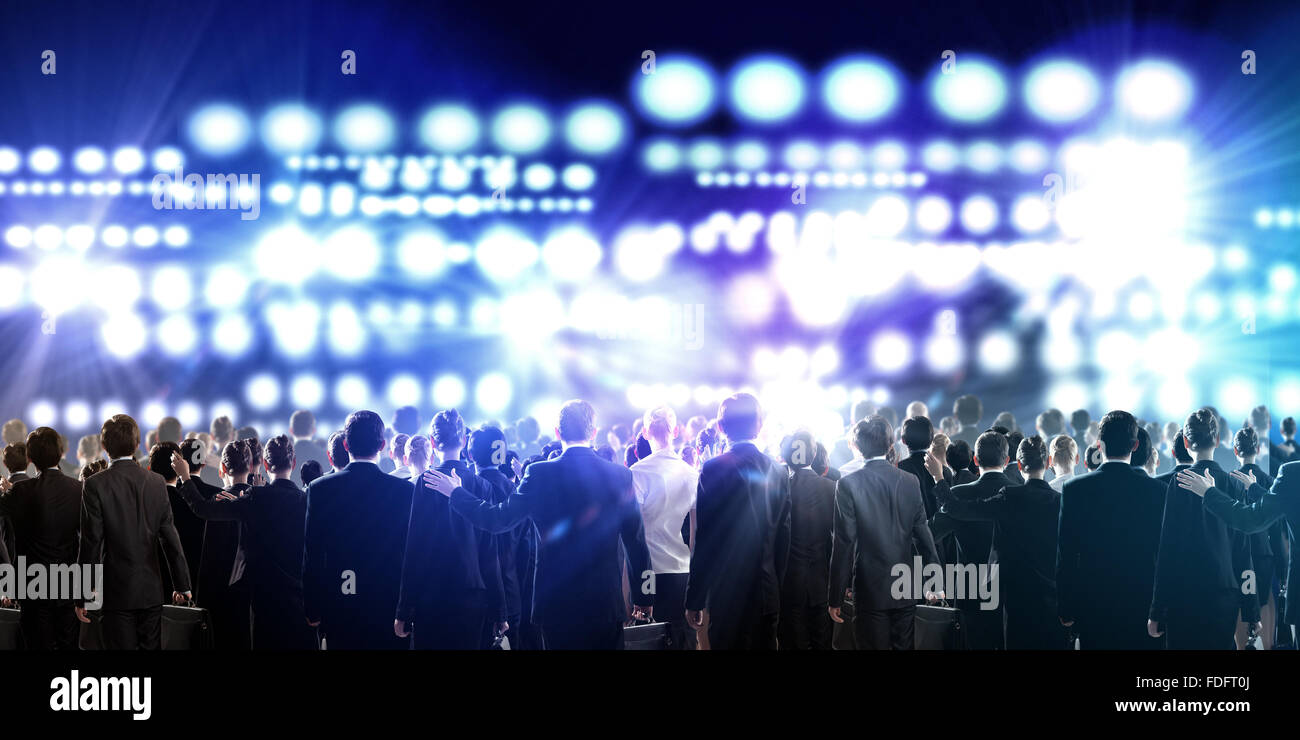 Crowd of businesspeople standing with back with lights at background ...