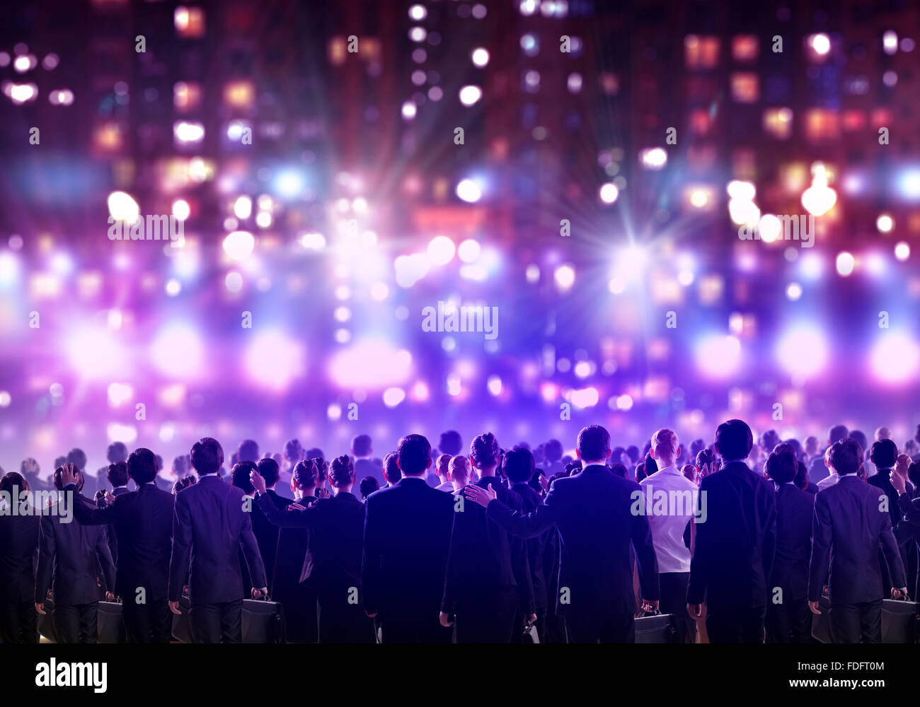 Crowd of businesspeople standing with back with lights at background ...