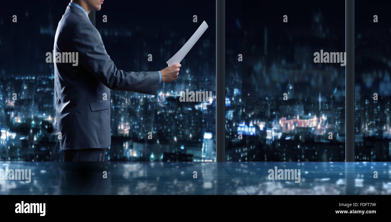 Businessman standing against office window reading documents Stock ...