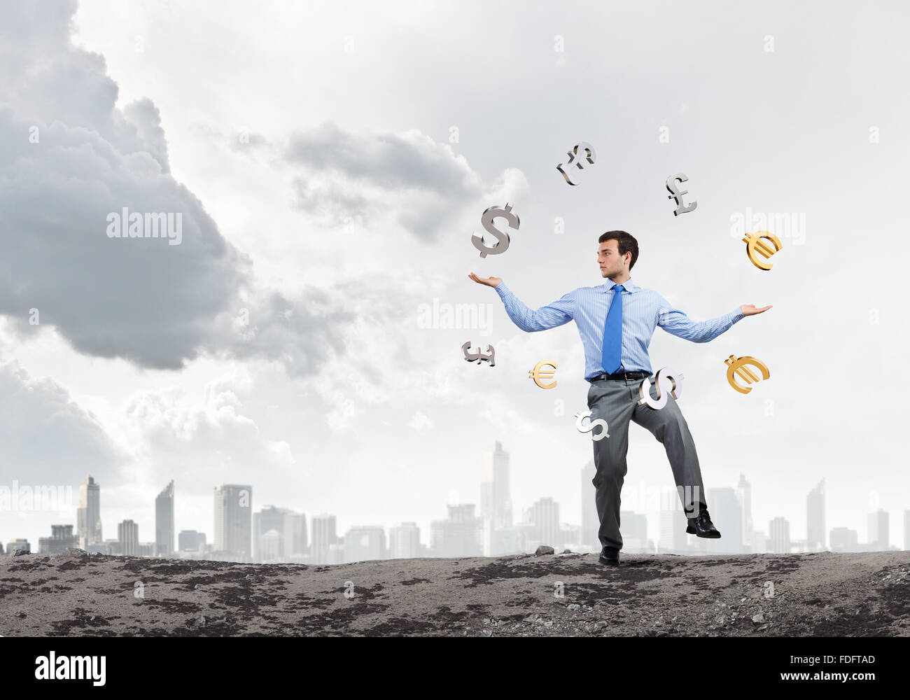 Young businessman juggling with currency symbols against city ...