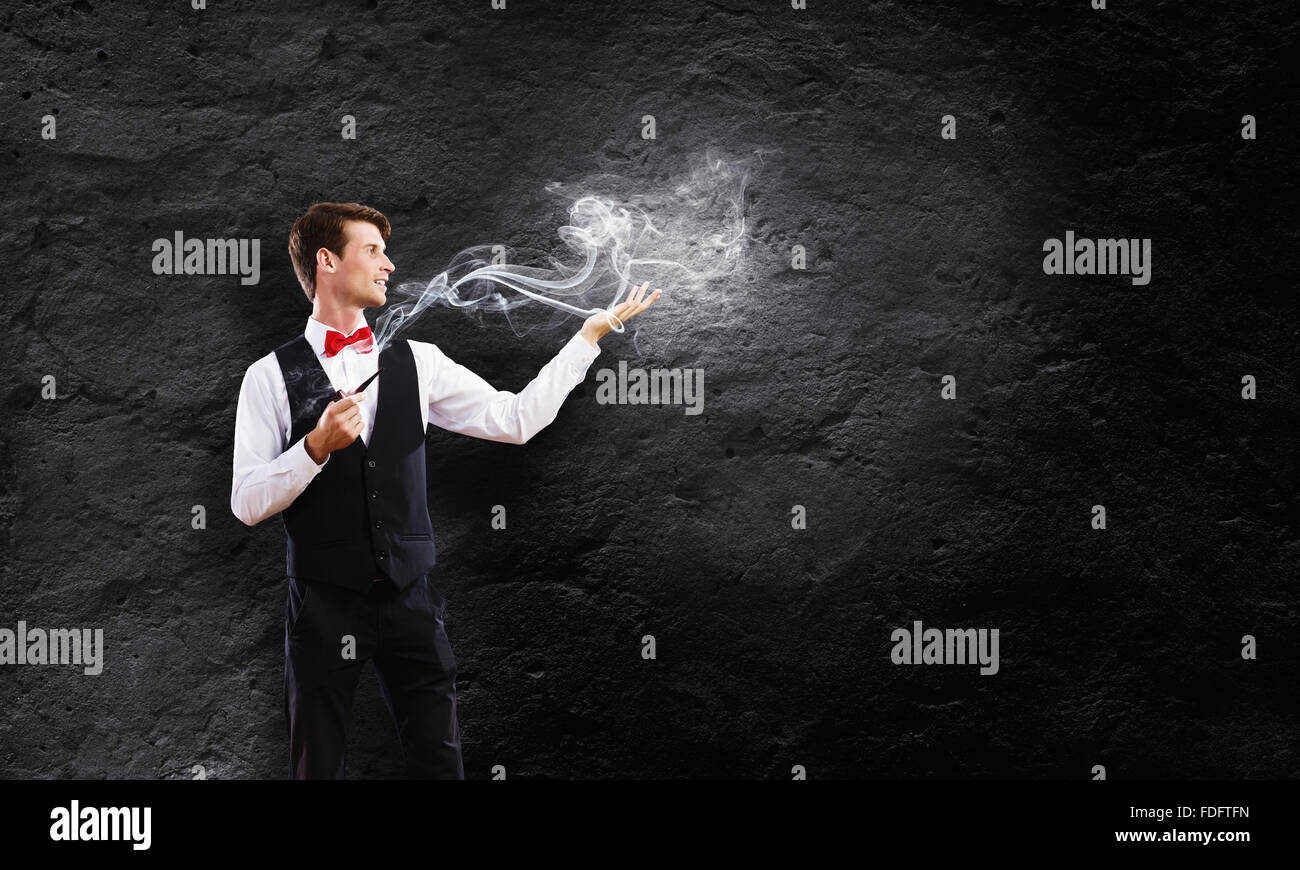 Young handsome businessman smoking pipe against black background Stock ...