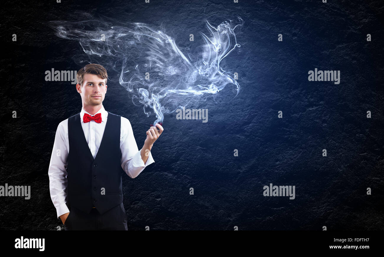 Young handsome businessman smoking pipe against black background Stock ...