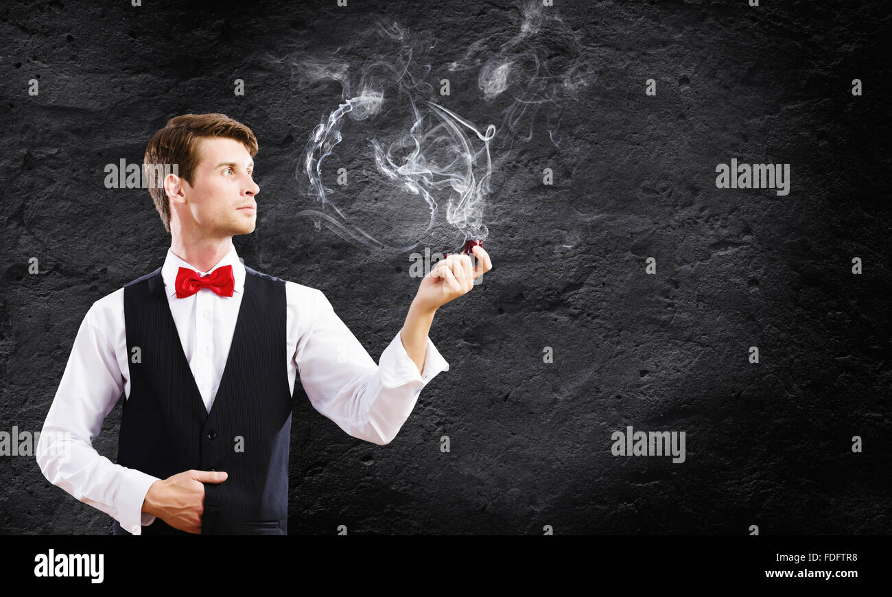 Young handsome businessman smoking pipe against black background Stock ...