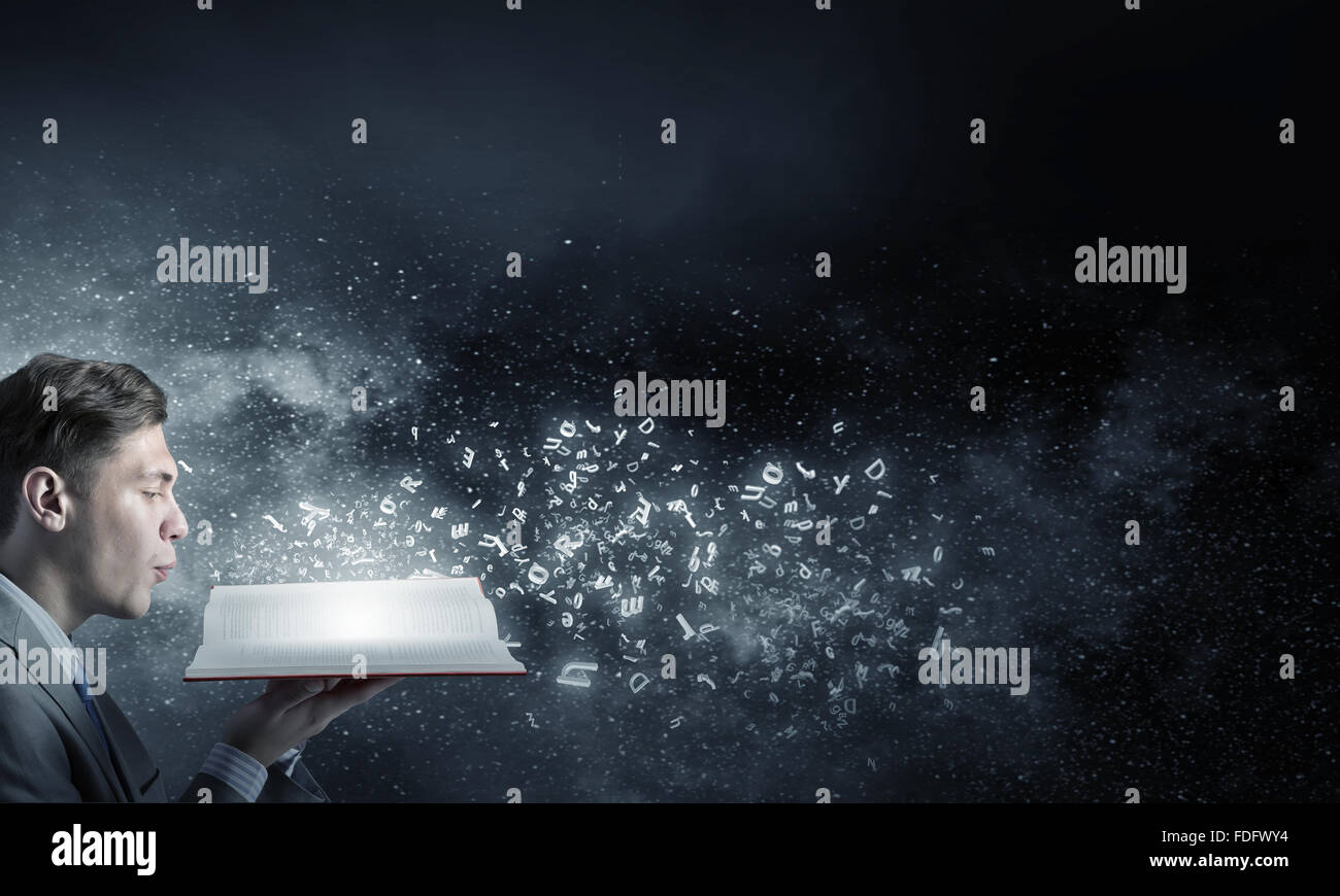 Young businessman with opened book in hands blowing on pages Stock ...