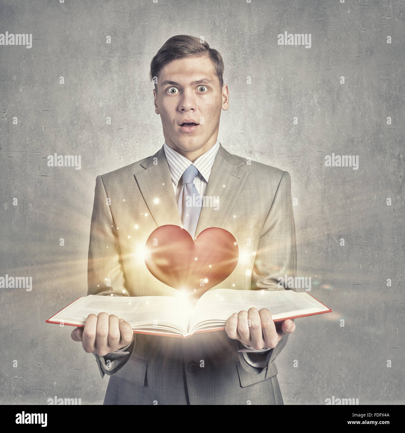 Young man in pile of books with one in hand Stock Photo - Alamy