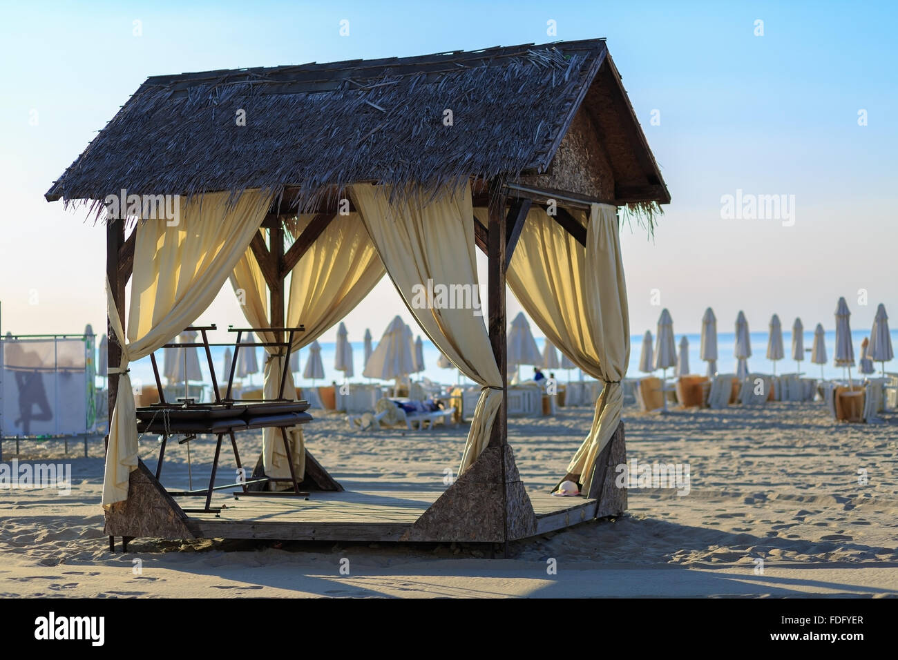 Massage canopy with thatched roof on the sandy beach. Early morning ...