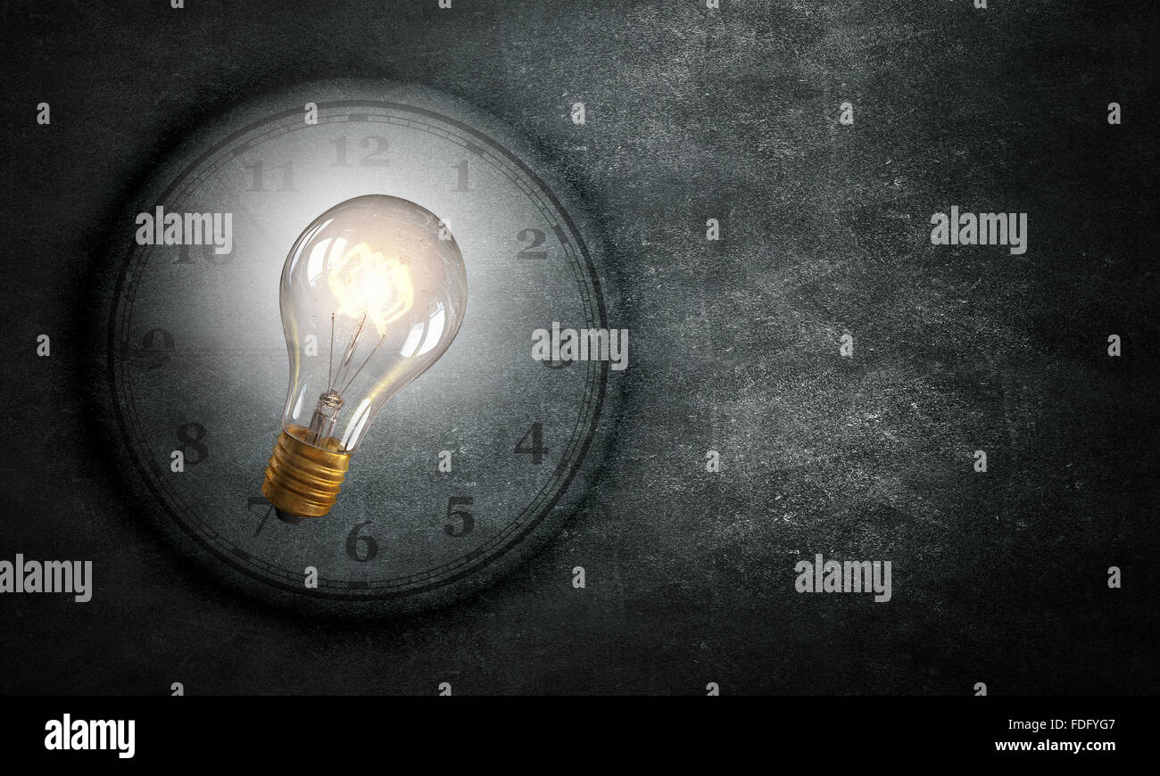 Conceptual image with light bulb and clock on dark background Stock ...